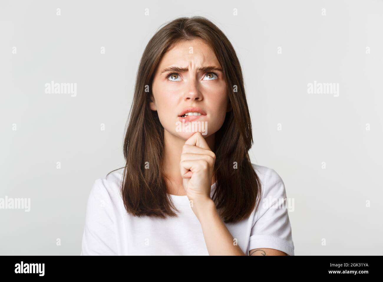 Close-up of puzzled cute thoughtful girl looking up and thinking ...