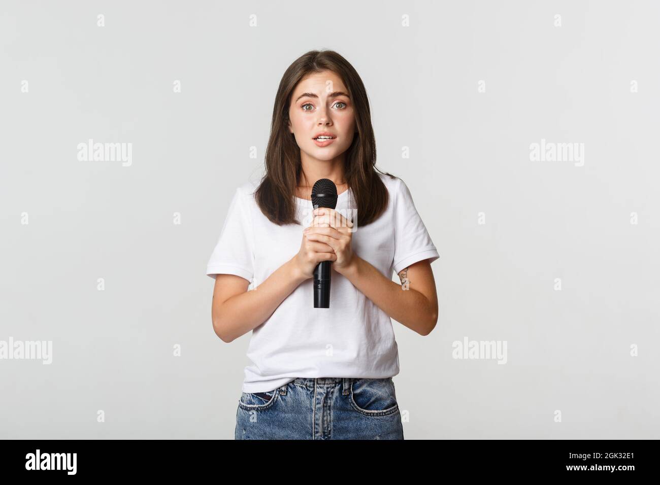 Shy cute brunette girl scared of singing in public, standing with ...