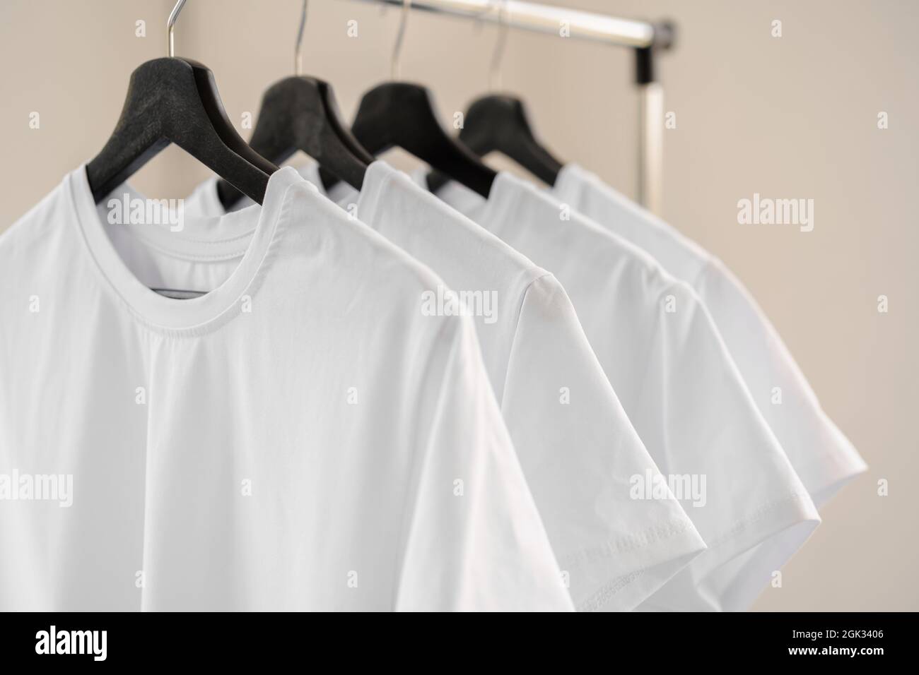 Row of white t-shirts on hangers on rack Stock Photo - Alamy