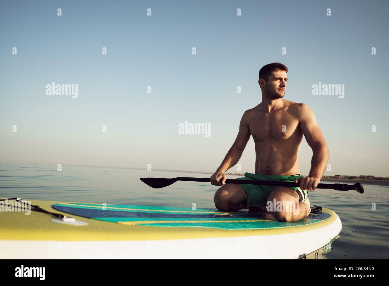 Young fit man on paddle board floating on lake Stock Photo - Alamy