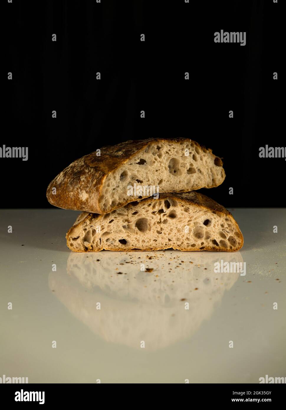 Bread cut in half on white table against black background Stock Photo ...