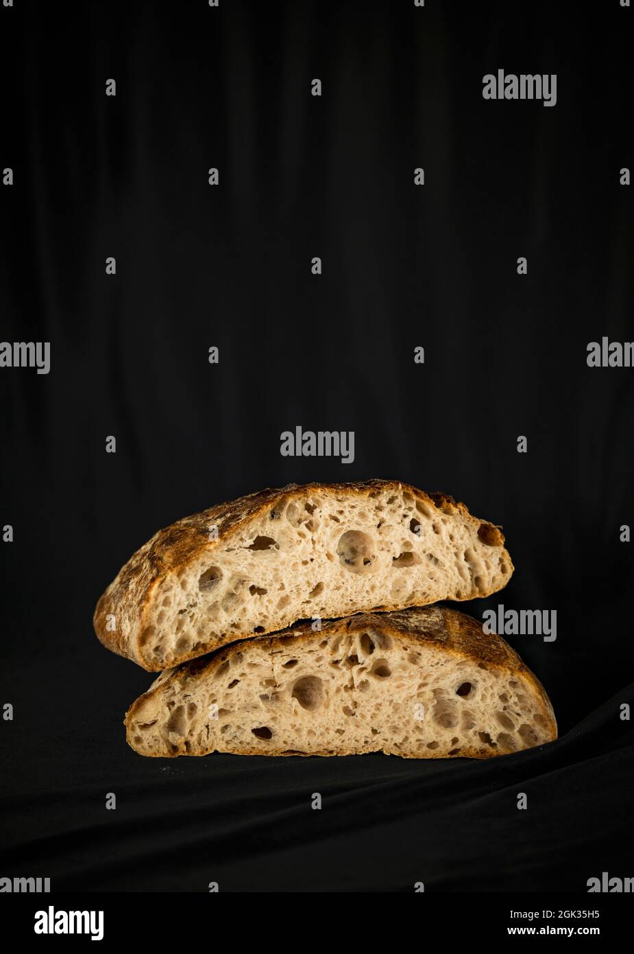 Bread cut in half against black background Stock Photo - Alamy
