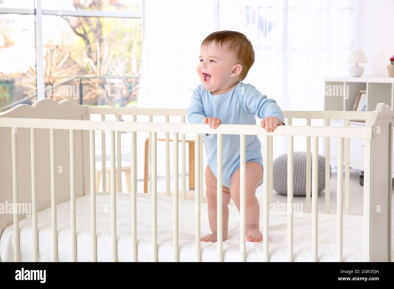 Cute little baby standing in crib at home Stock Photo - Alamy