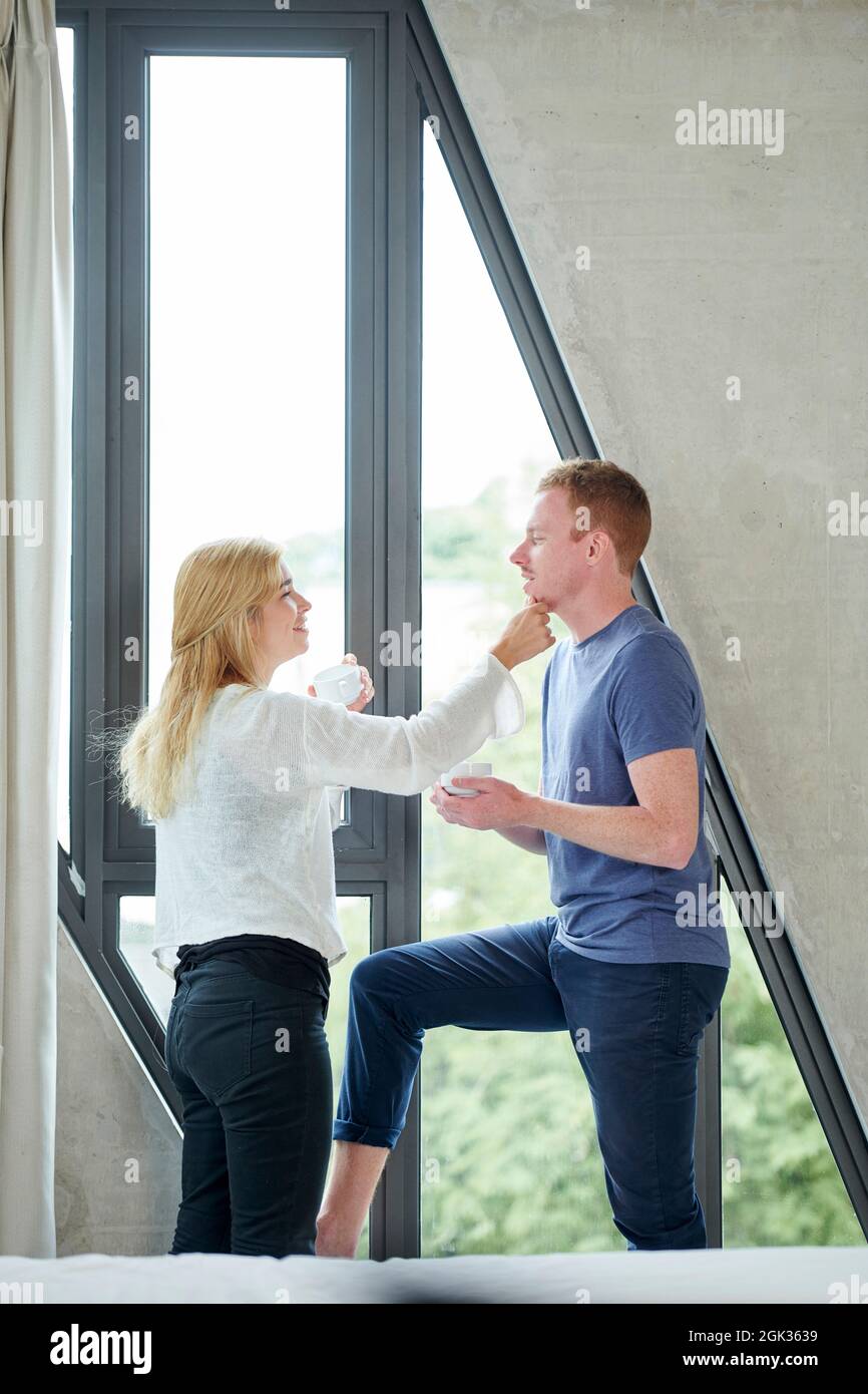 Cheerful young boyfriend and girlfriend in love standing at big ...