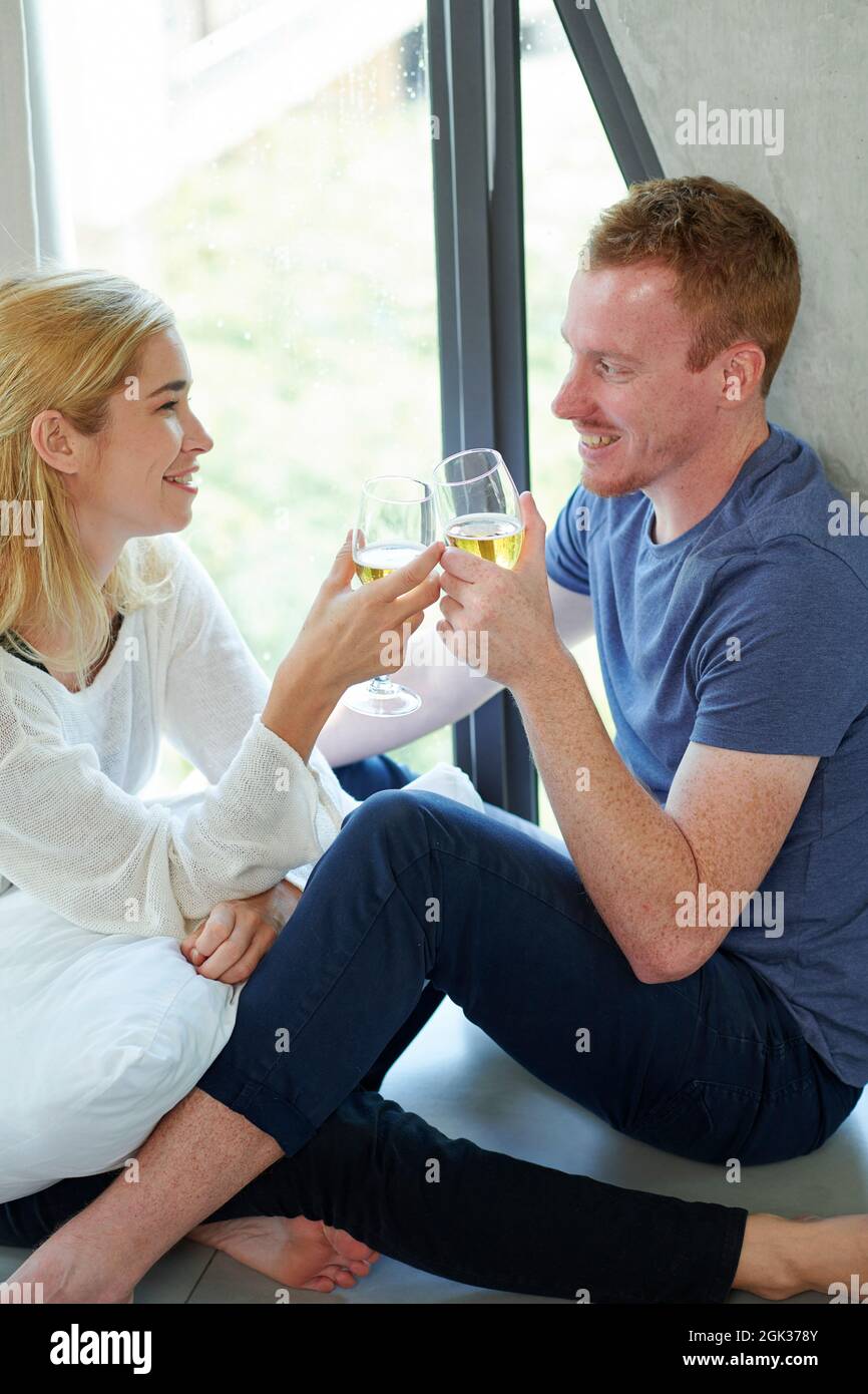 Young boyfriend and girlfriend sitting on window sill with champagne ...