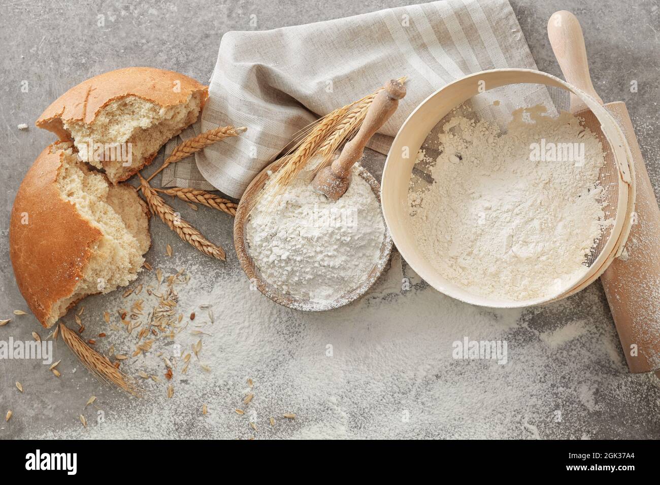Bowl with flour, sieve and bread chunk on light background Stock Photo ...
