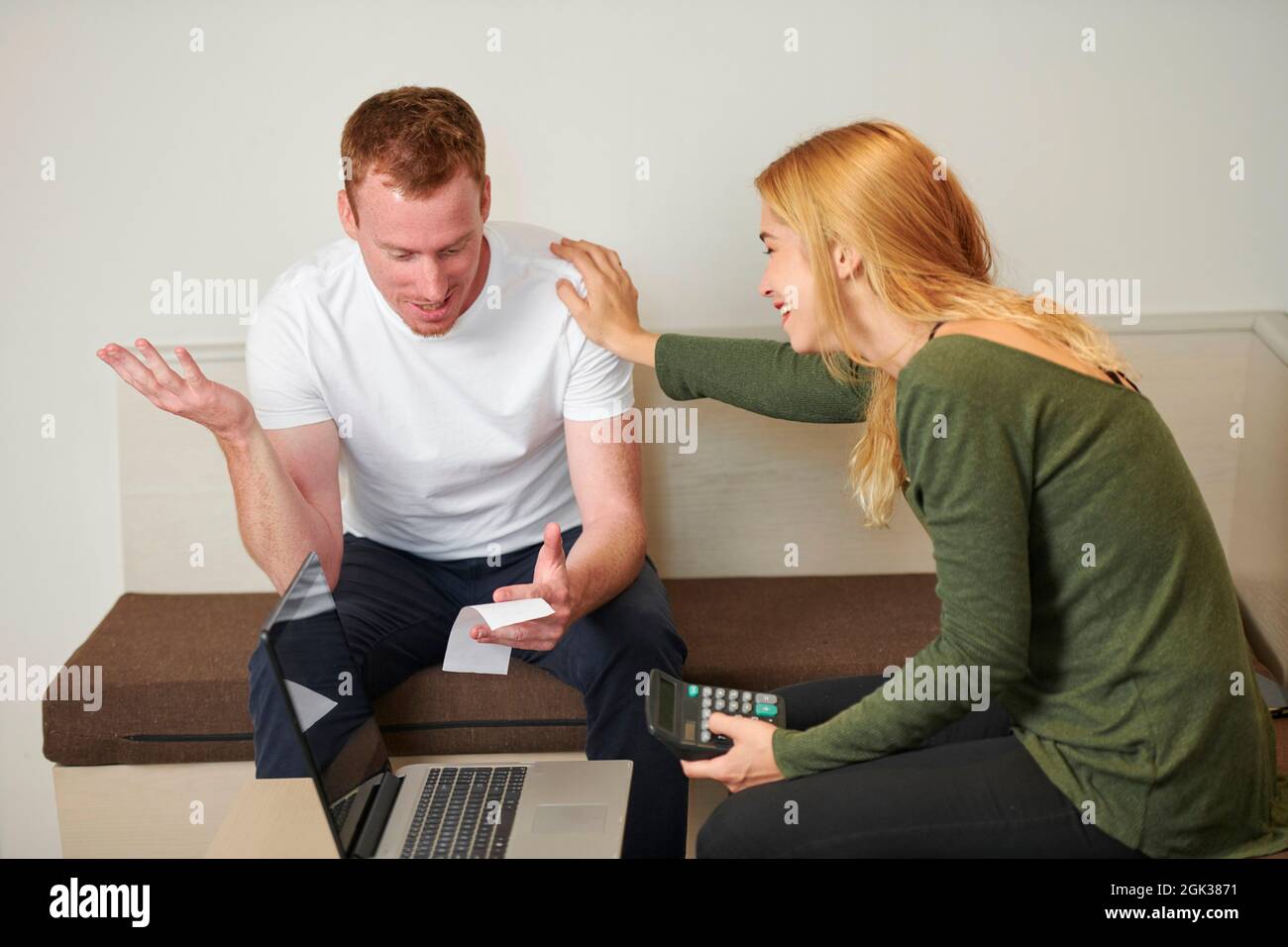 Confused laughing young couple trying to figure out where the big bills ...