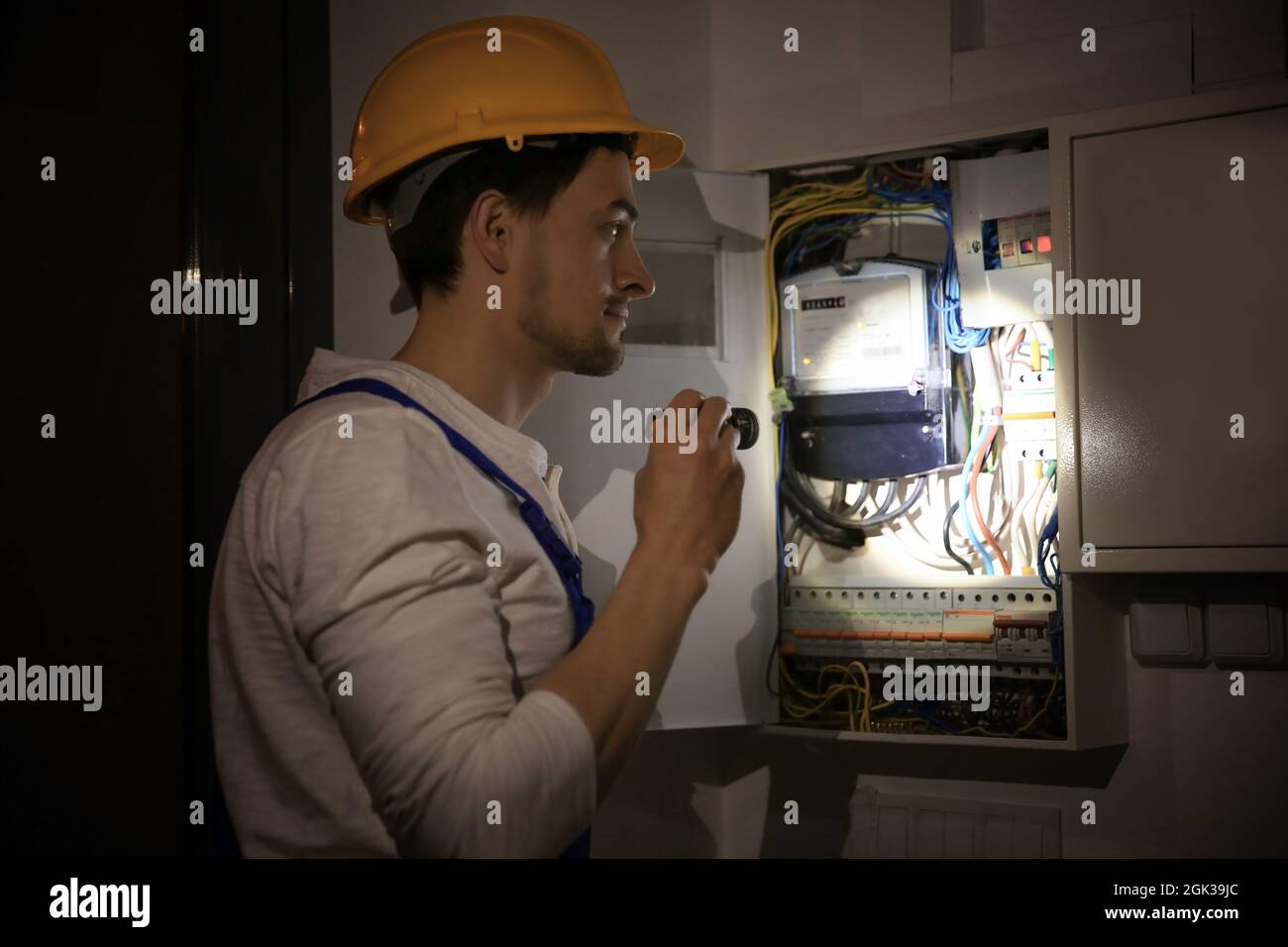 Young electrician with flashlight near switch box in dark room Stock ...