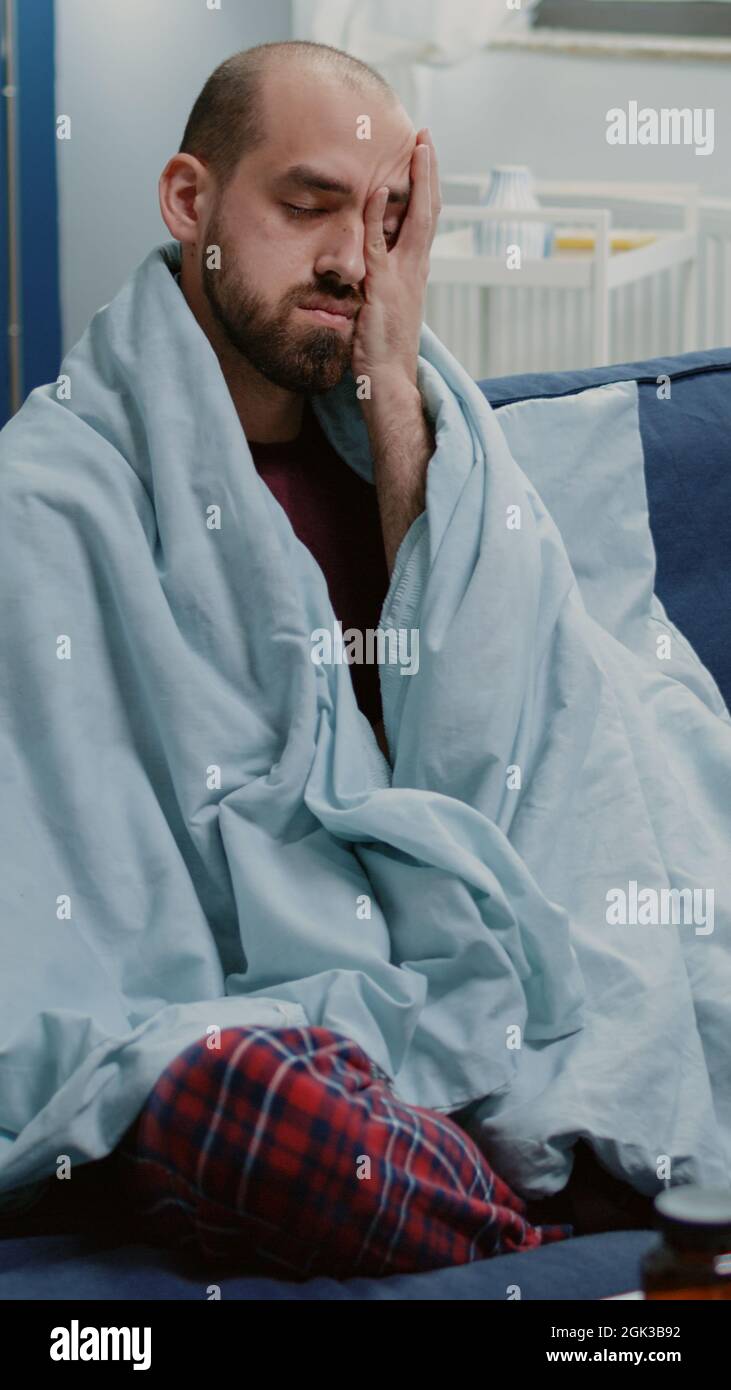 Unwell man having headache wrapped in blanket at home. Ill person with ...