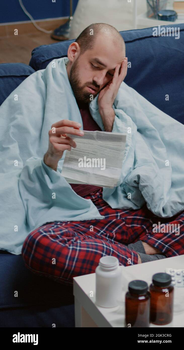 Man with sickness reading medicament information leaflet to heal cold ...