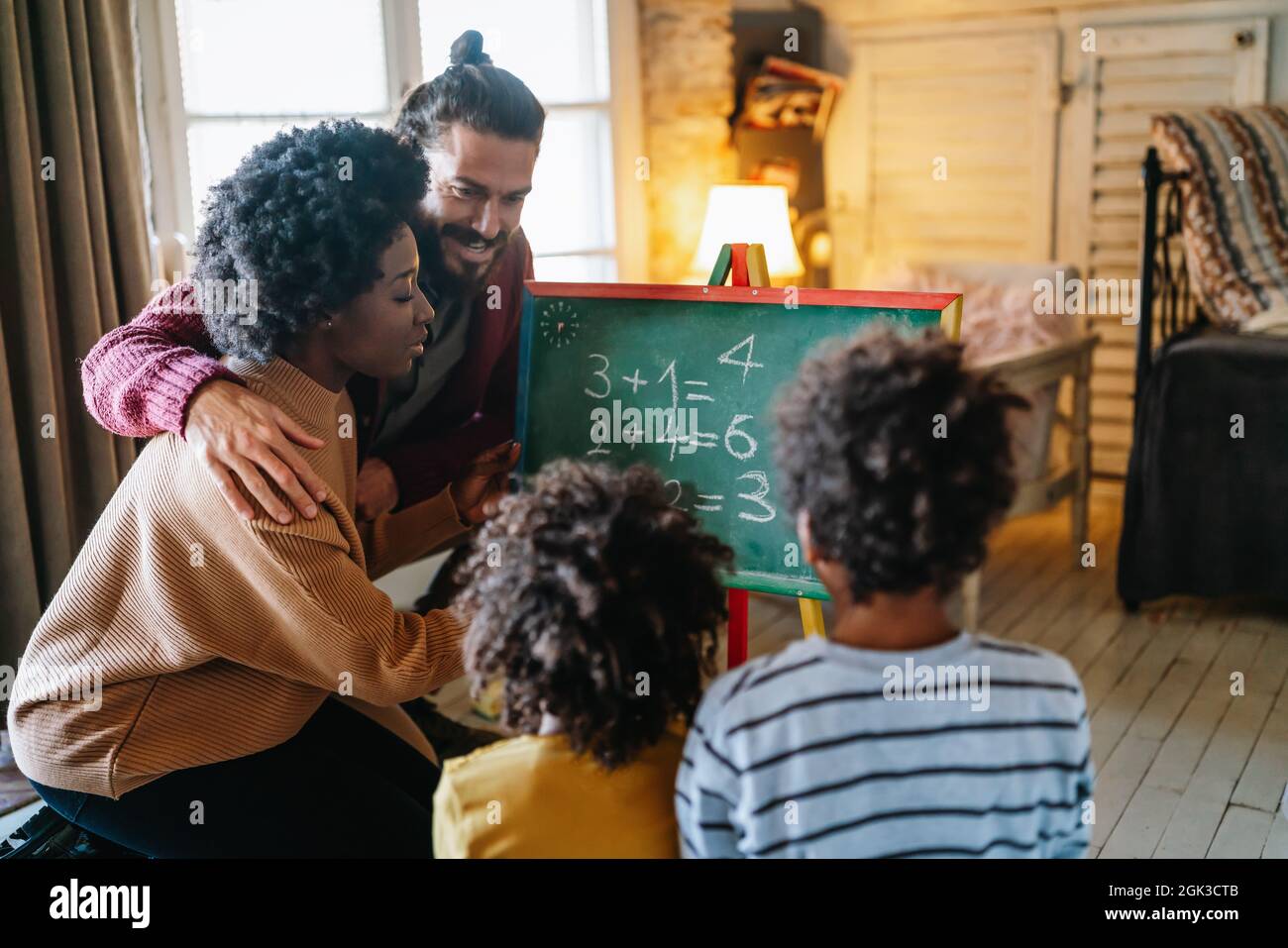 Happy children learning maths with multiethnic parents at home. Family ...