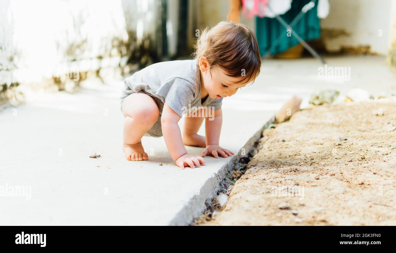 adorable one year old boy trying to stand up to take his first steps ...