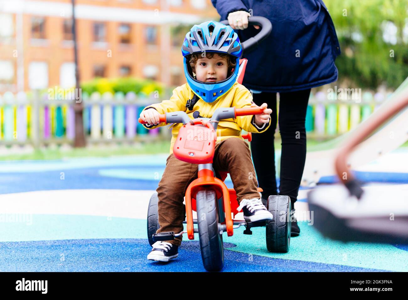 three year old boy riding a tricycle with a helmet in a park Stock ...