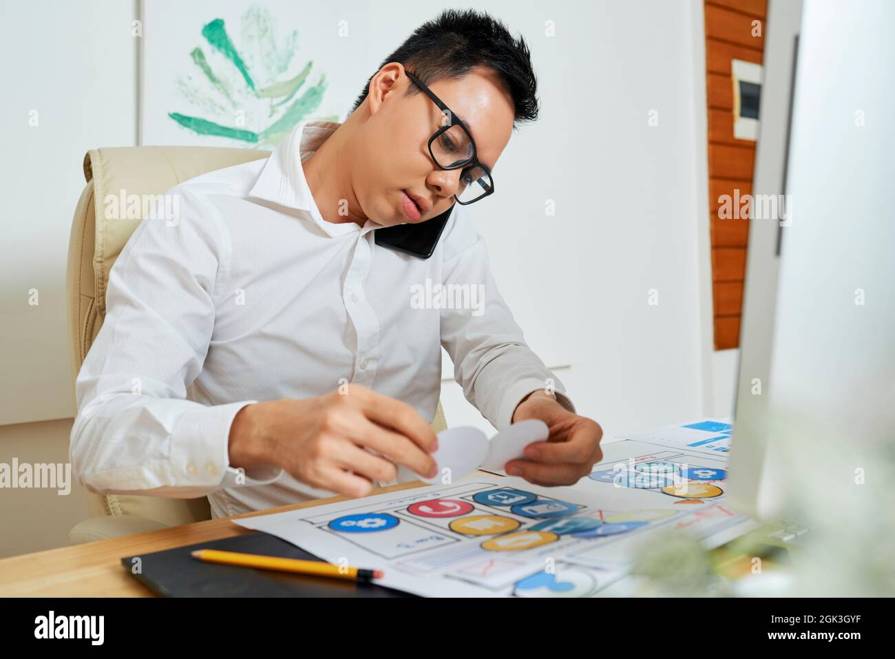 Graphic designer talking on phone with customer or colleague when ...