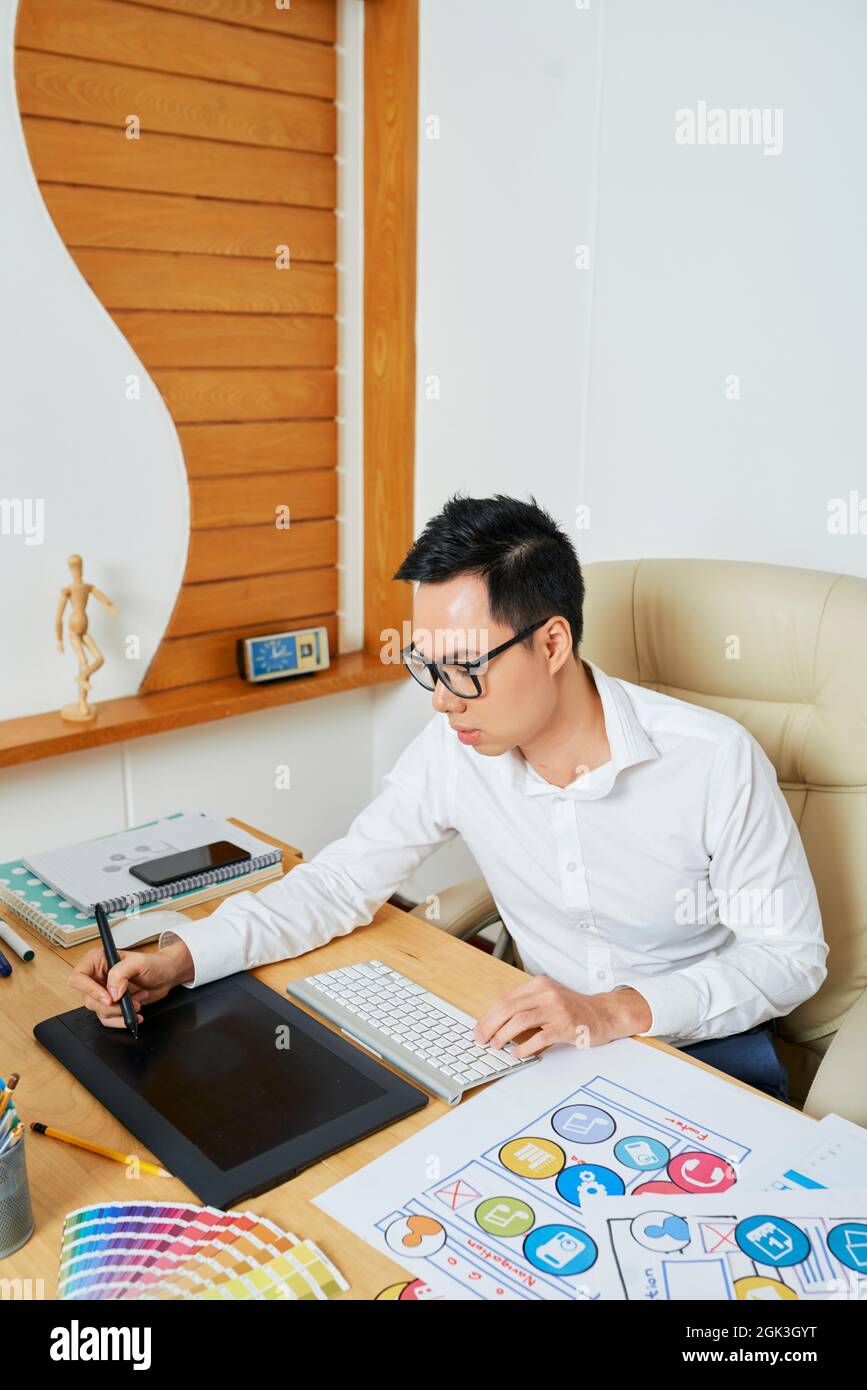 UI designer using graphic tablet when when drawing set of icons for new ...