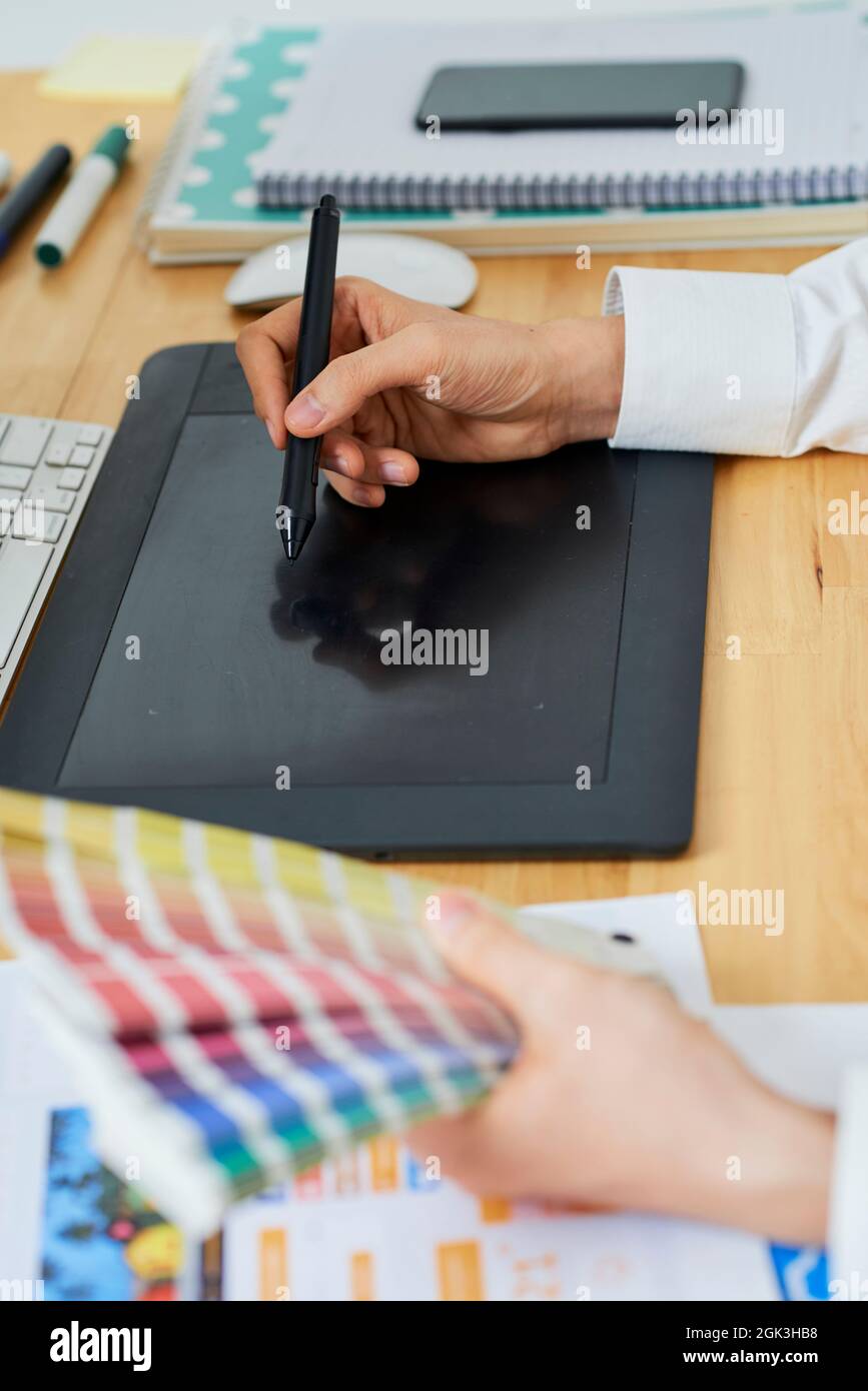 Graphic designer holding palette of color samples when drawing picture ...
