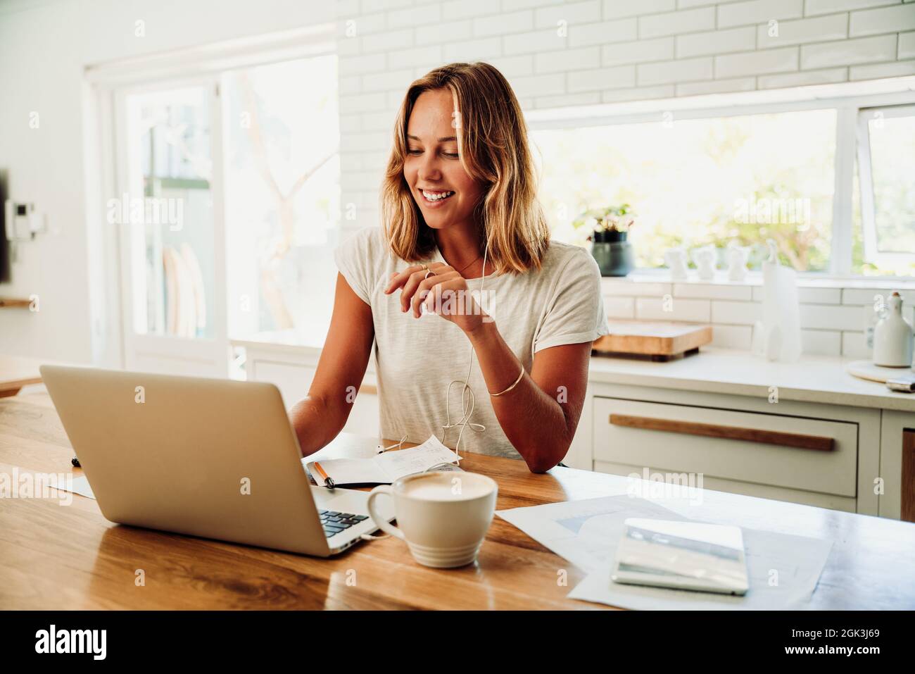 Caucasian female student typing on laptop smiling while on video call ...