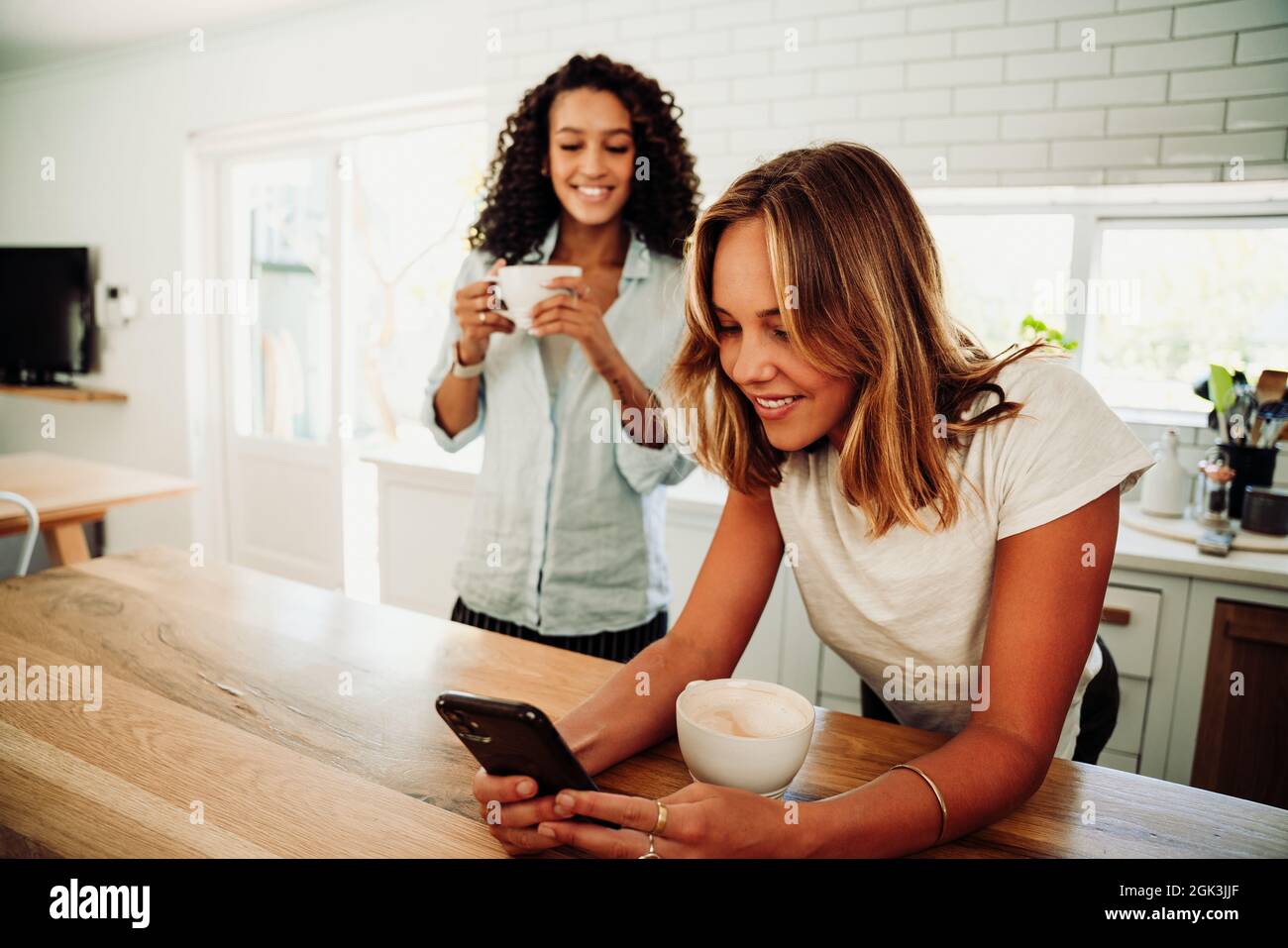 Mixed race friends chatting in kitchen bonding together typing on ...
