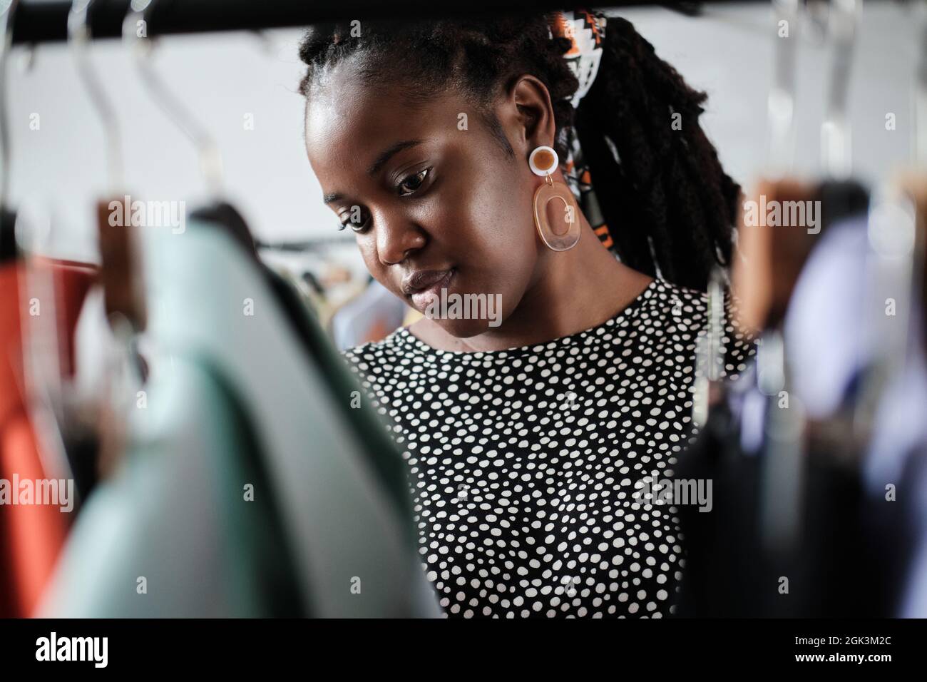 African young woman choosing new clothes on the rack during shopping in ...