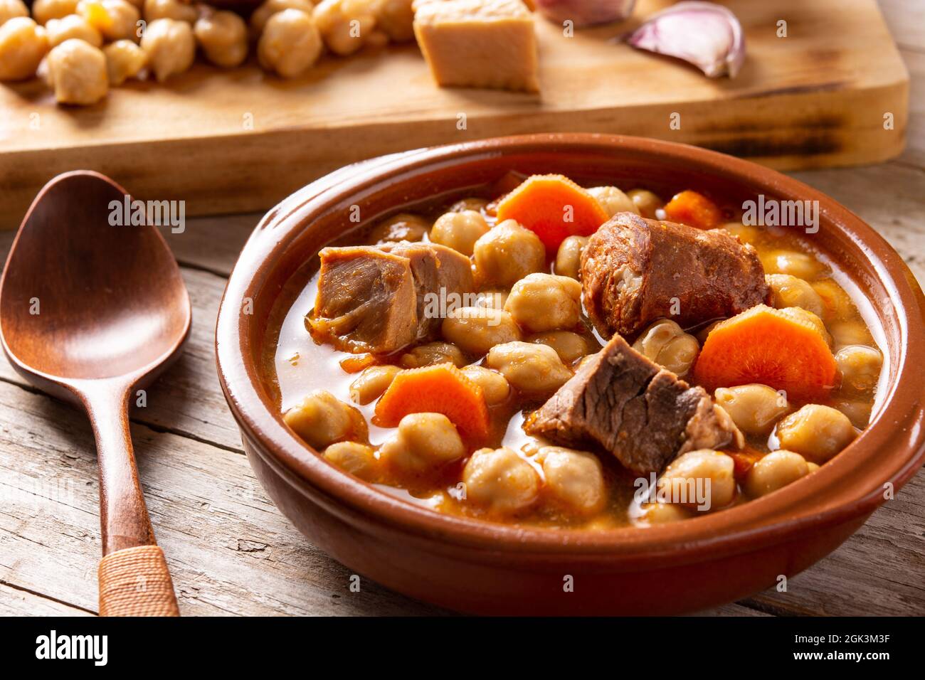 Traditional Spanish cocido madrileño. Chickpea stew on wooden table ...
