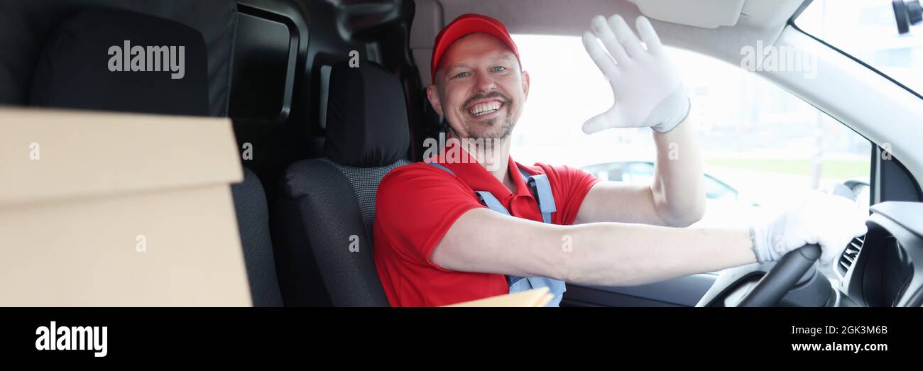 Male driver courier in cab of car waving his hand in greeting Stock ...