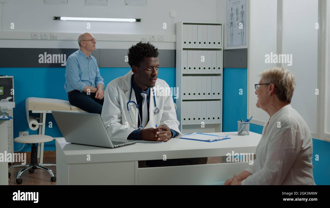 Medic of african american ethnicity doing examination with sick elder patient at healthcare ...
