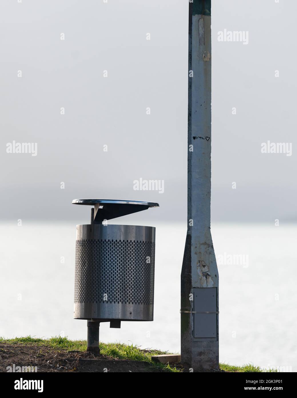 Galvanised rubbish bin and lamp post on the beach. Vertical format ...
