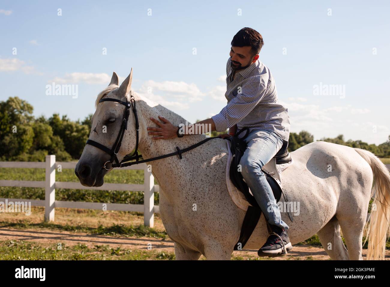 The handsome man rides a horse on a ranch Stock Photo - Alamy
