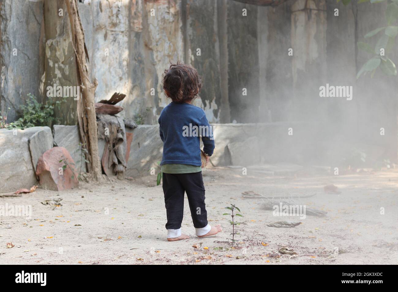 Close-up back view photo of A small Indian child playing blowing mud ...