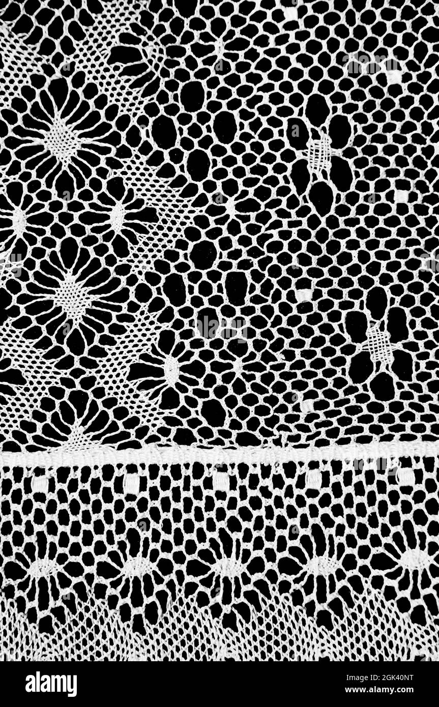 Vertical shot of white handmade lace isolated on a black background ...
