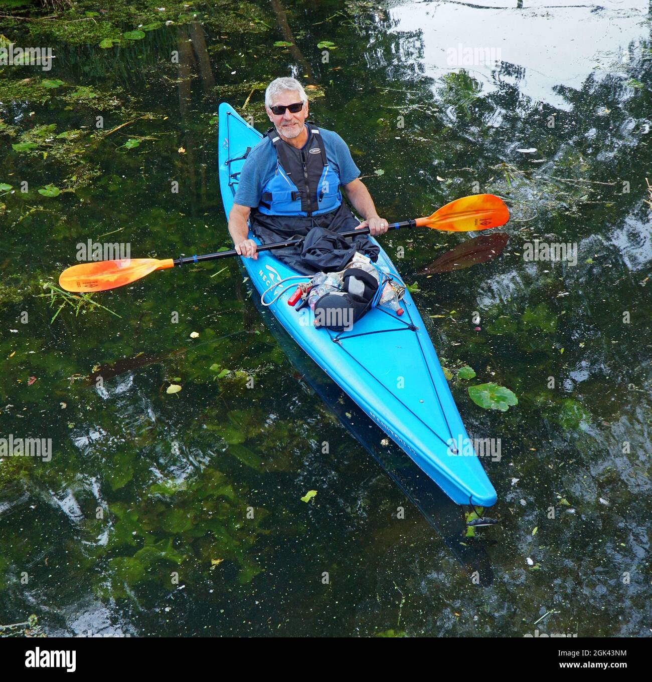 Man in Kayak collecting rubbish cleaning up brook Stock Photo - Alamy