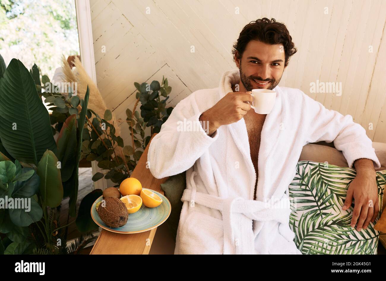 Handsome man drinking wellness tea while relaxing at exotic spa resort ...