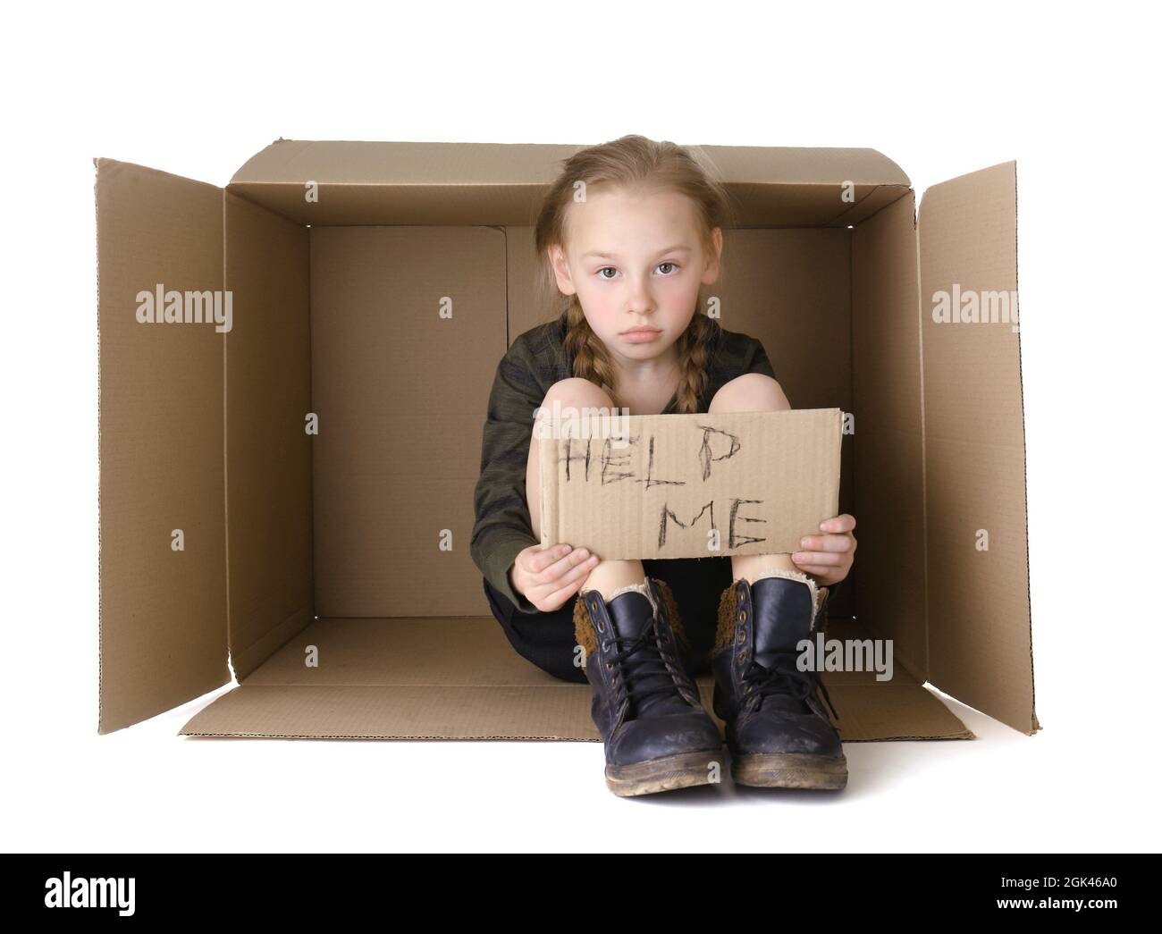 Poor little girl with piece of cardboard sitting in cardboard box on ...