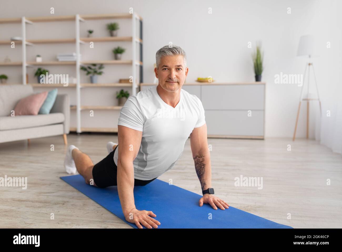 Mature man stretching back muscles, doing sphinx cobra pose or upward ...