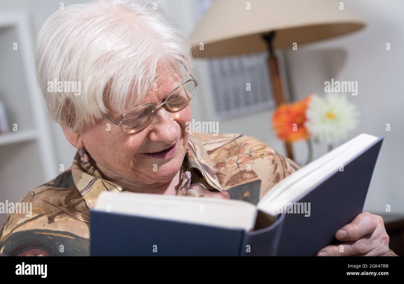 Old woman reading a book at home Stock Photo - Alamy