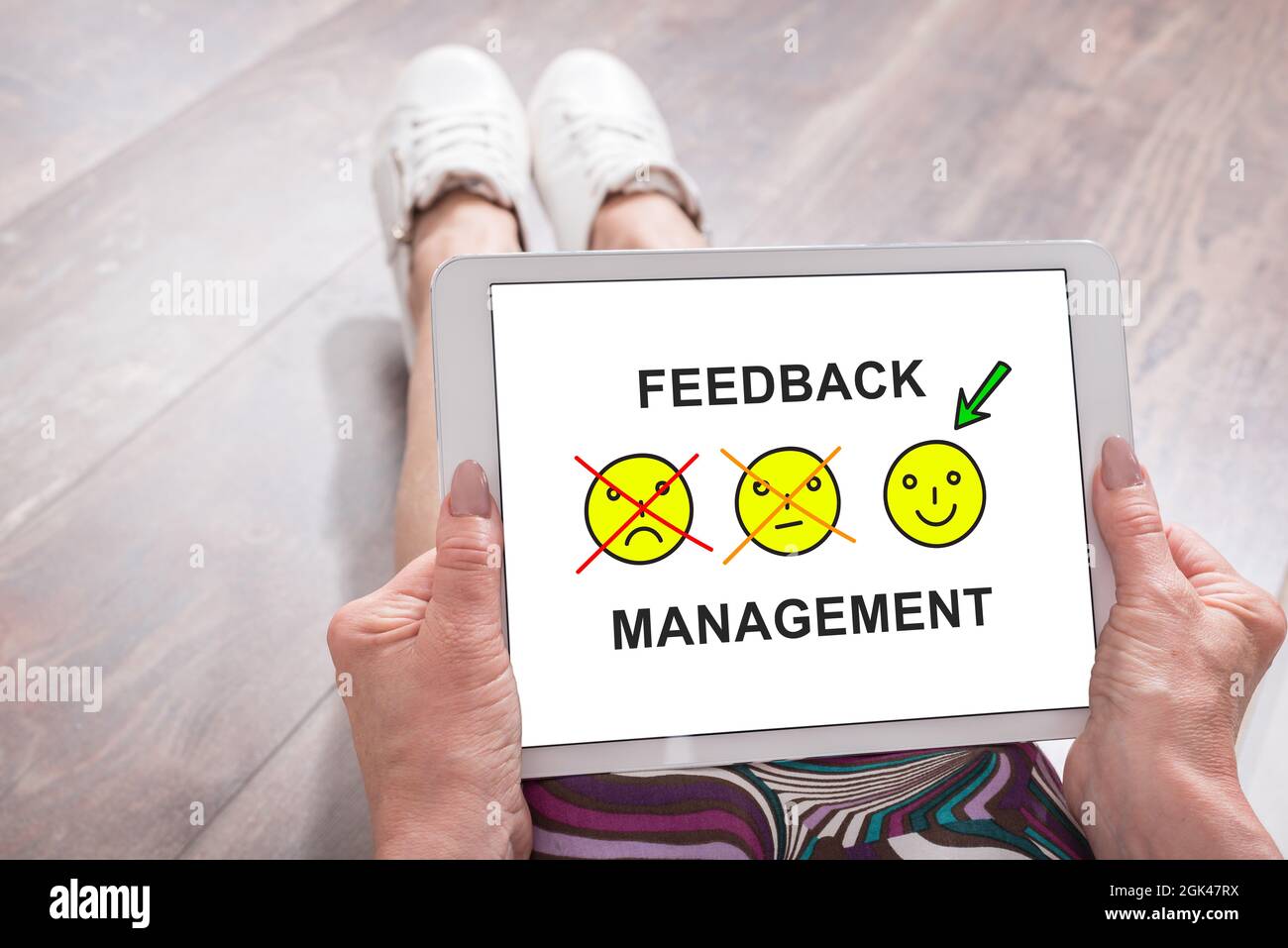 Woman sitting on the floor with a tablet showing feedback management ...