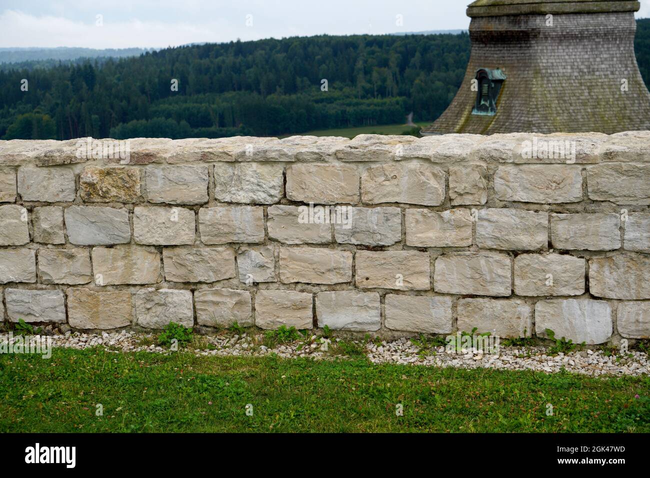 Shot of a stone wall in front of a building top and a forest Stock ...