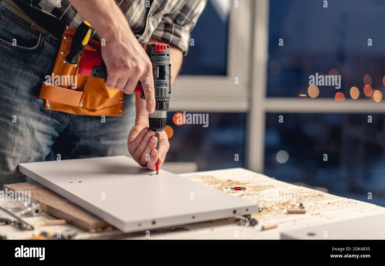 Man working making holes in board with drill during process of ...