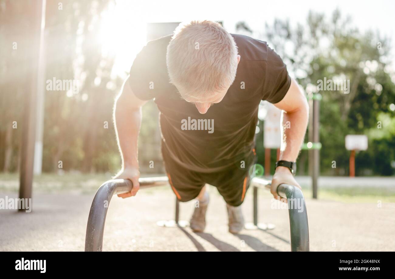 Strong man guy training and doing push ups with horizontal bar with ...