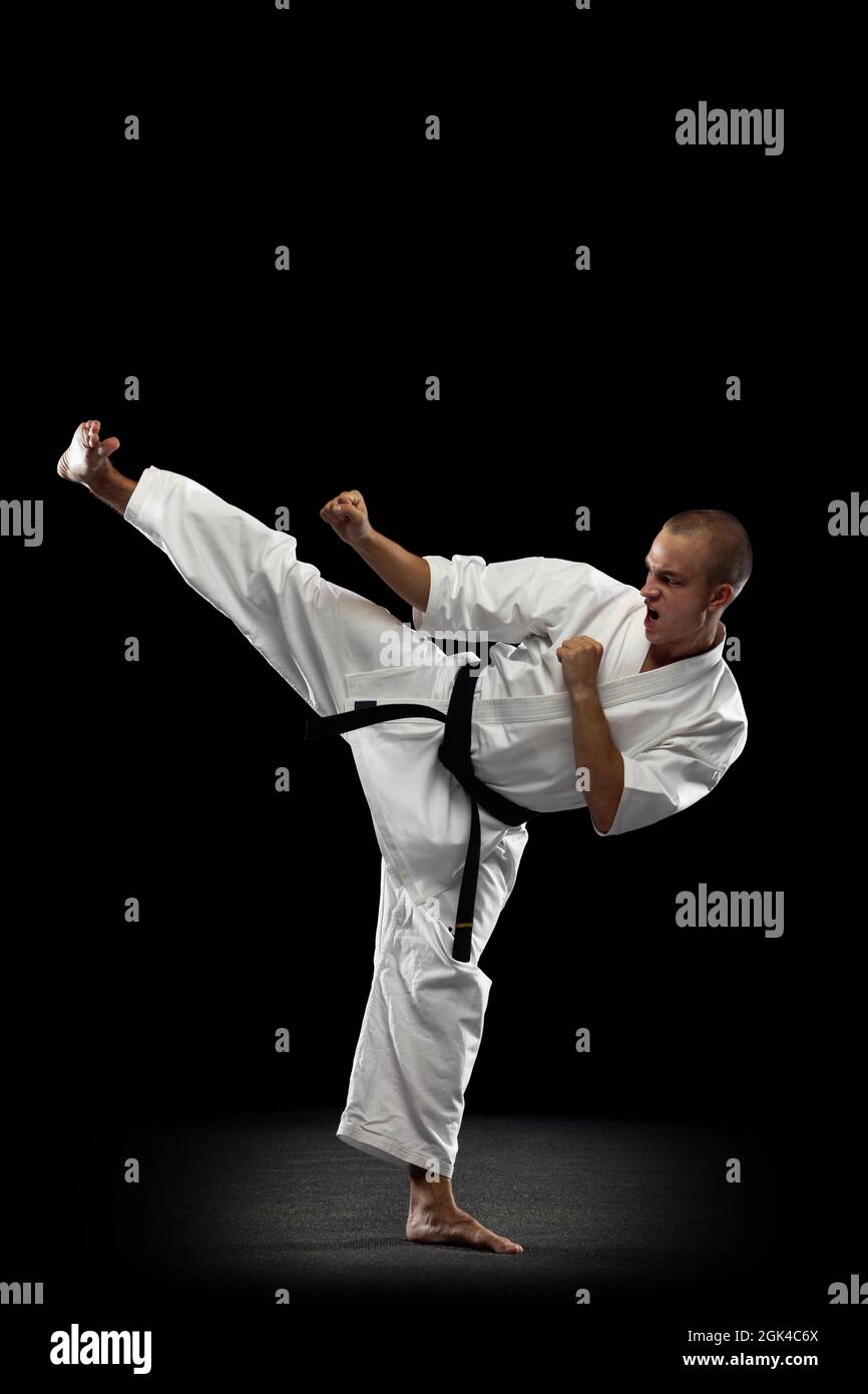 Full-length vertical portrait of young sportsman practising karate ...