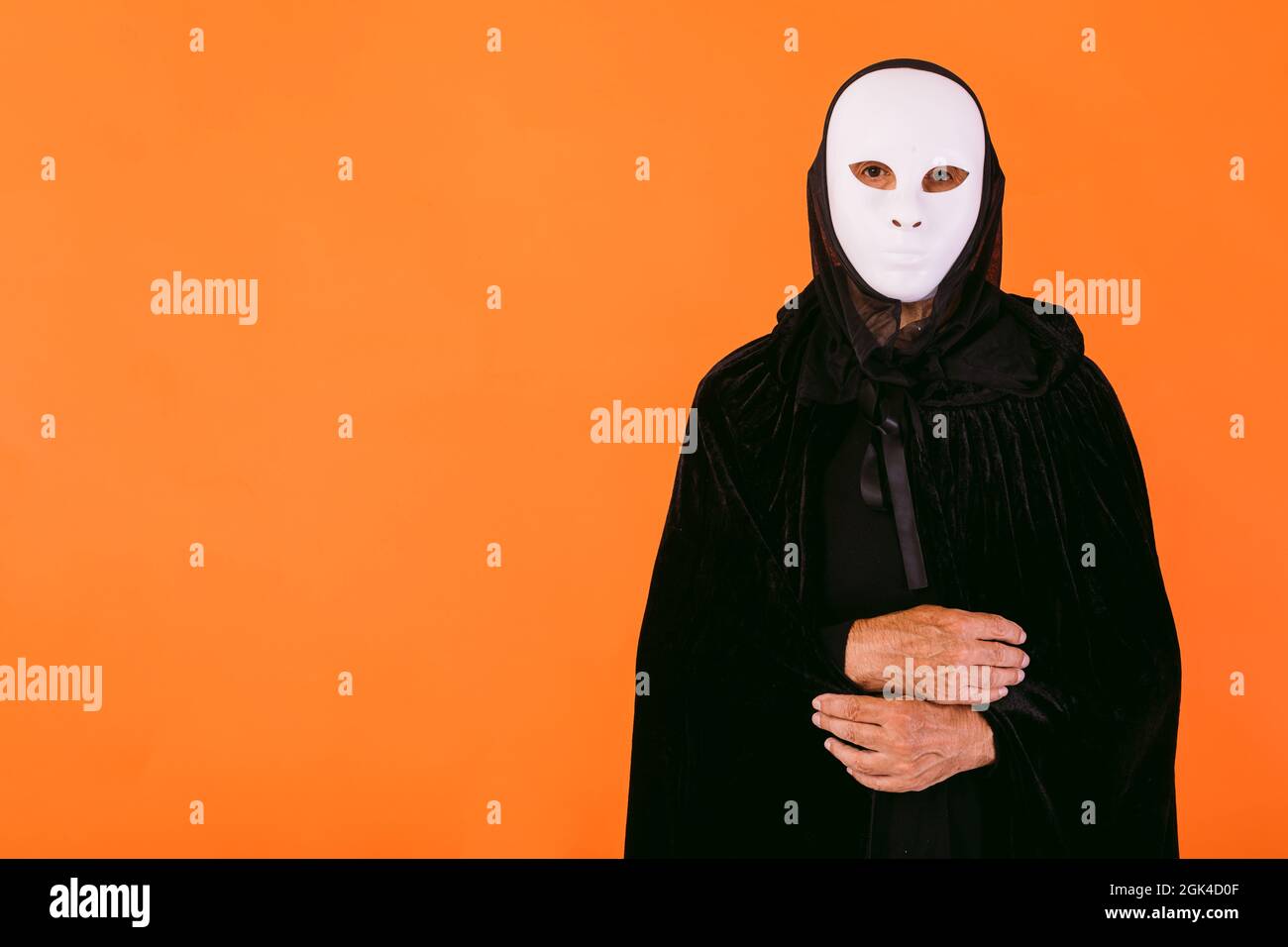 Portrait of a person in white killer Halloween mask, cape and hood ...