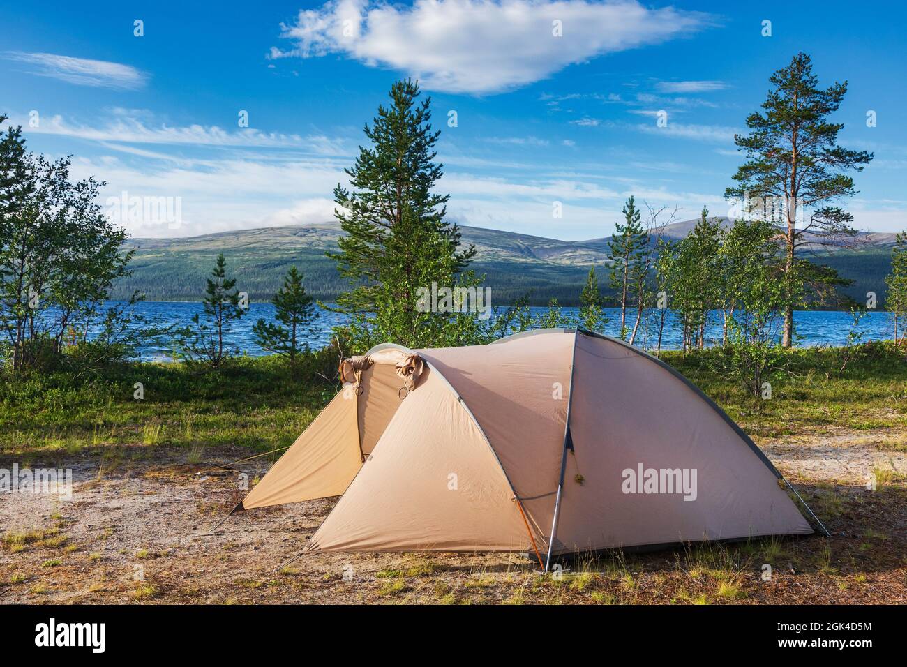 Camping tent at scenic campsite on a lakeshore with a mountain range in ...