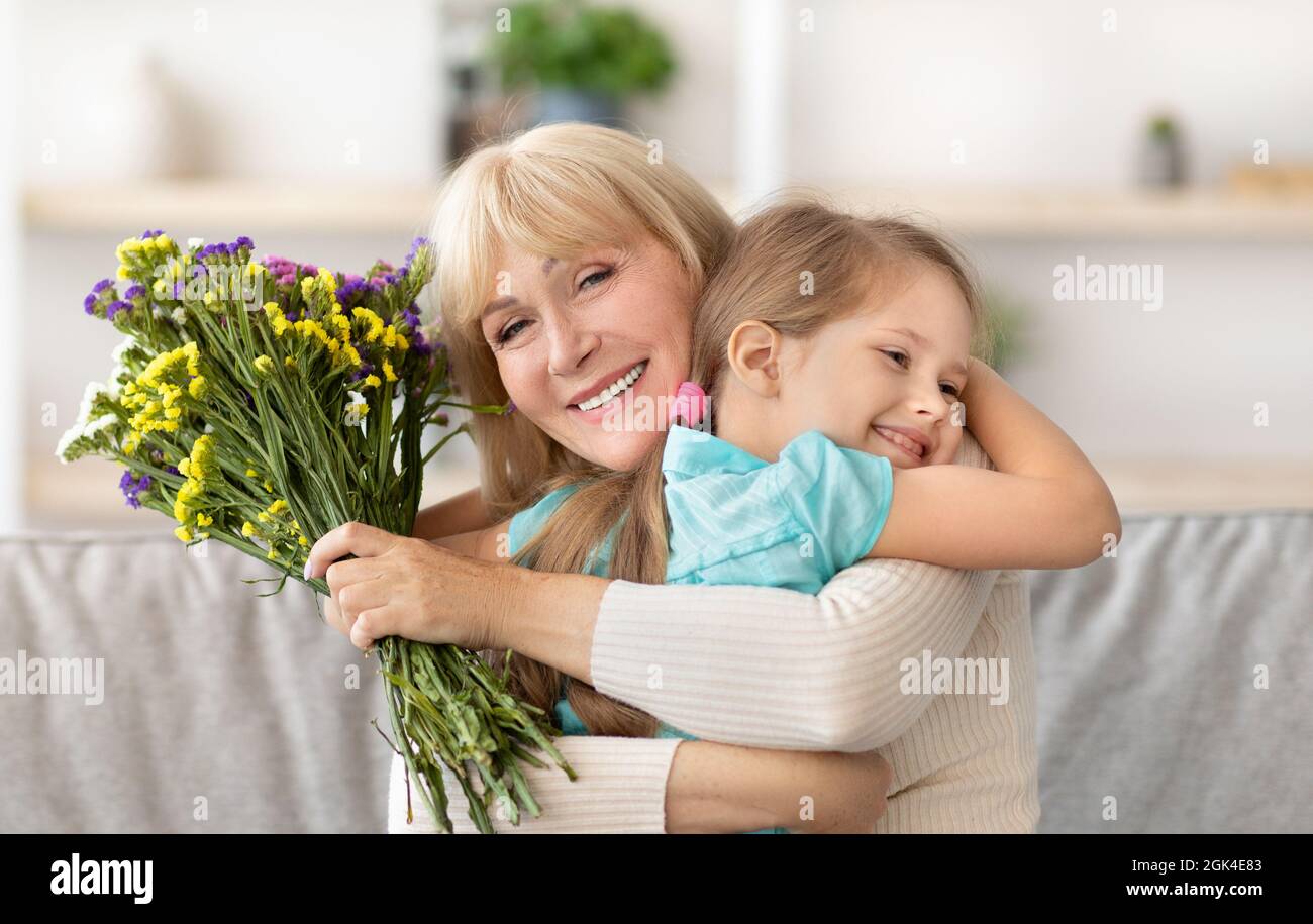 Happy little child greeting happy aged woman with flowers Stock Photo ...