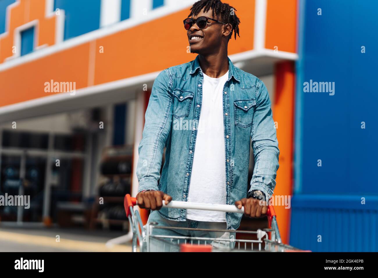 afro american black man with shopping cart in front of mall shopping ...