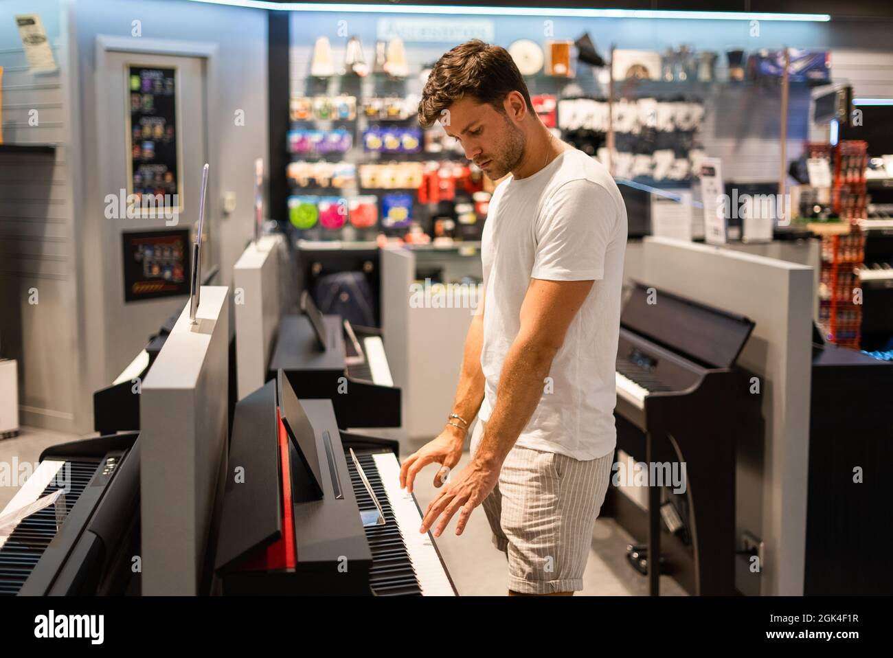 Side view of young male client playing electric piano while visiting ...