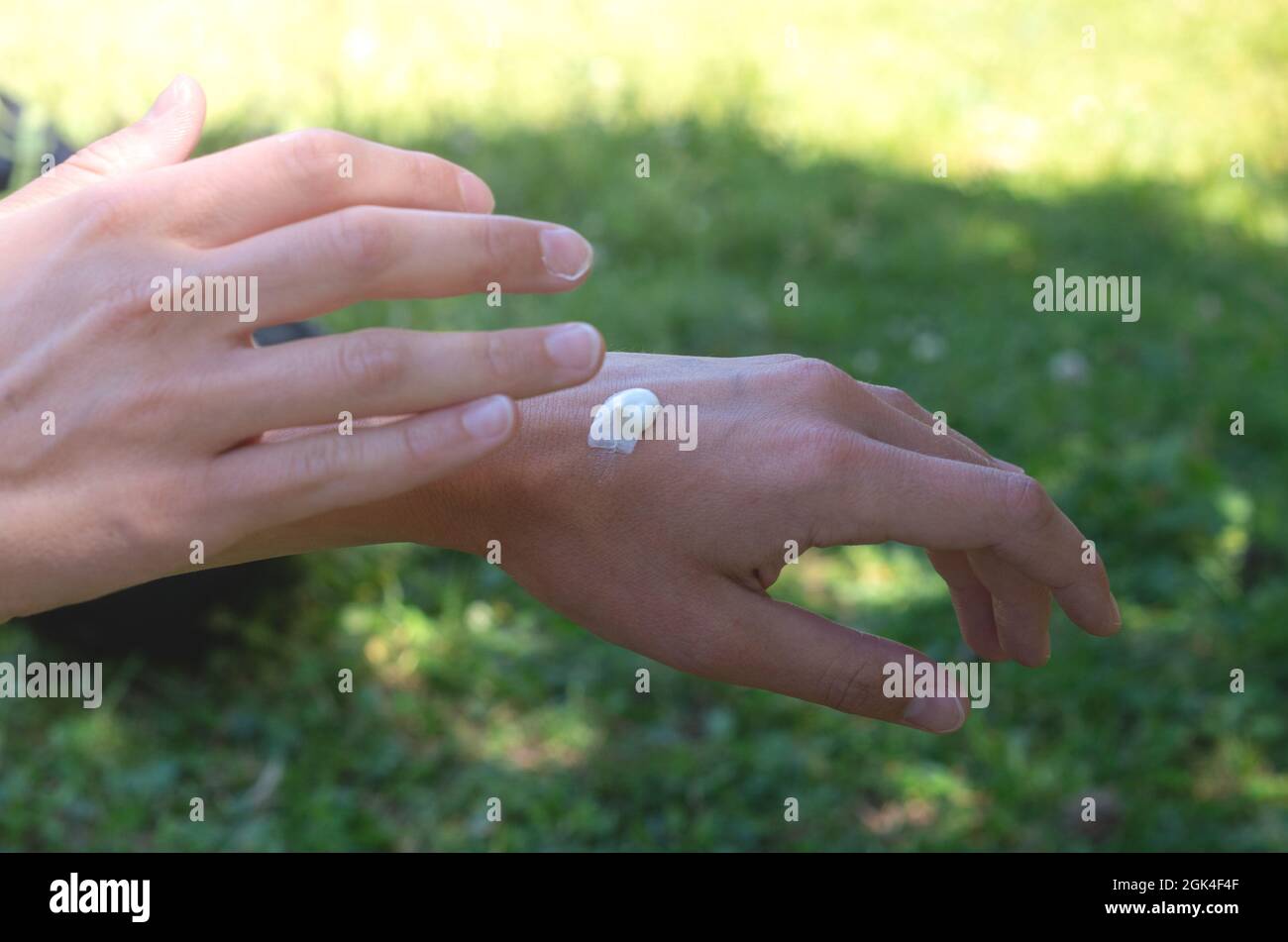 Woman's hand with skincare cream on nature background. Female hands use ...