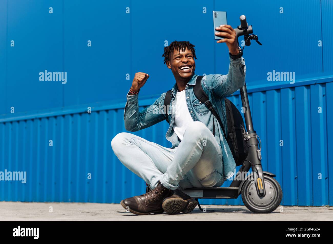 black African American sits on an electric scooter, and takes a selfie ...