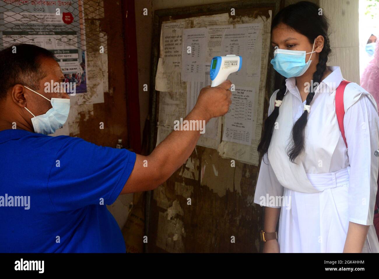 An official checks the body temperature of a student upon her arrival ...