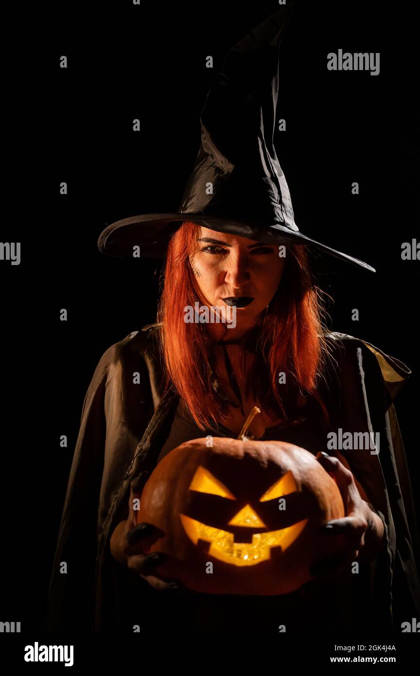 Wicked witch holding a jack-o-lantern for halloween Stock Photo - Alamy