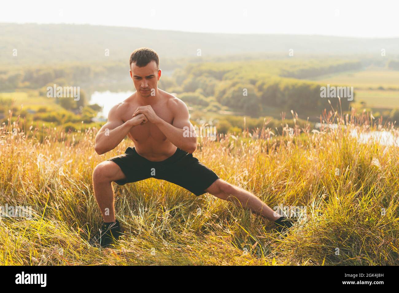 Young strong man is stretching outdoors in the nature on a beautiful ...
